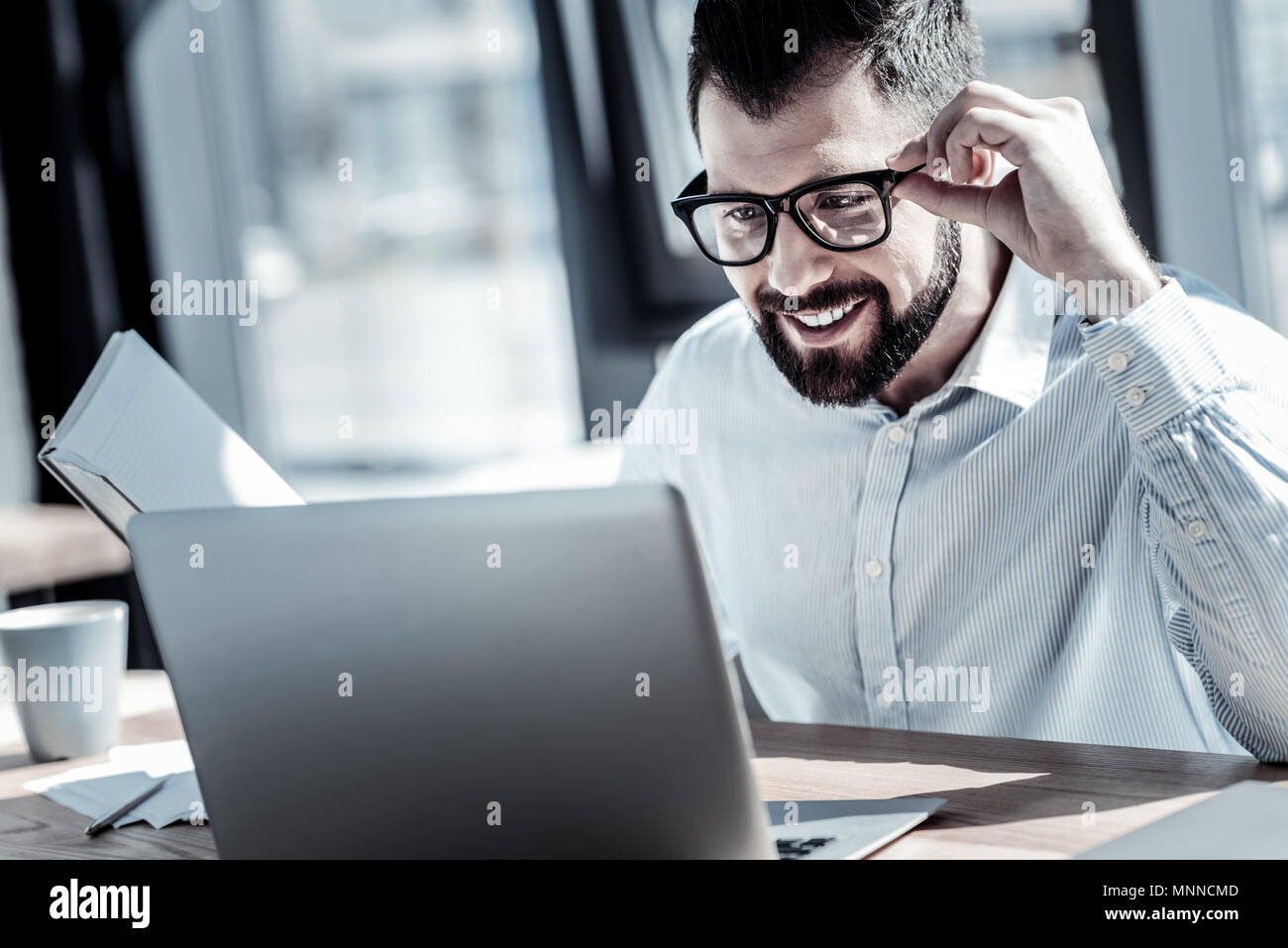 Joyful bespectacled man touching his glasses and smiling Stock Photo ...