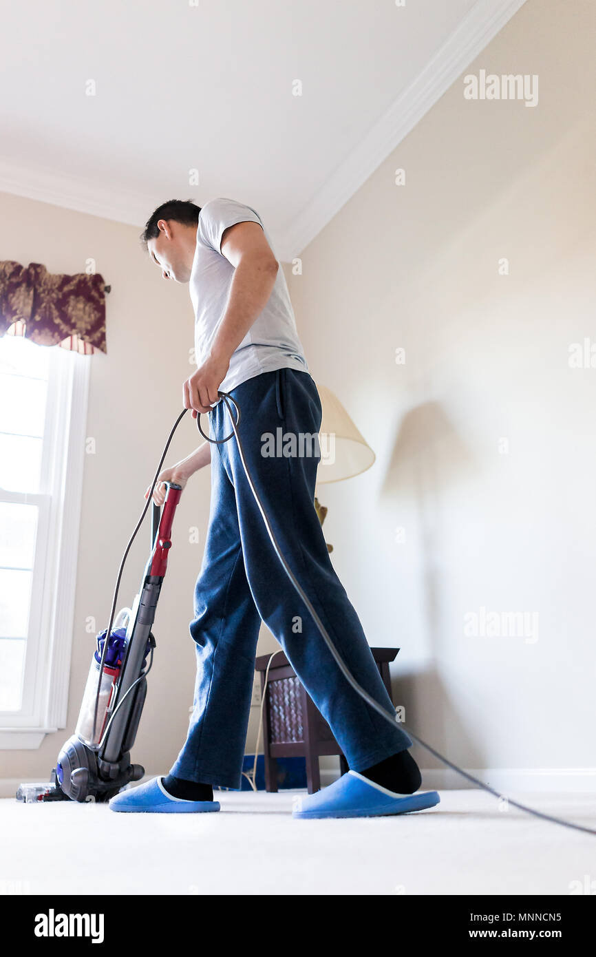 Young man house husband stay at home dad vacuuming using vacuum on ...