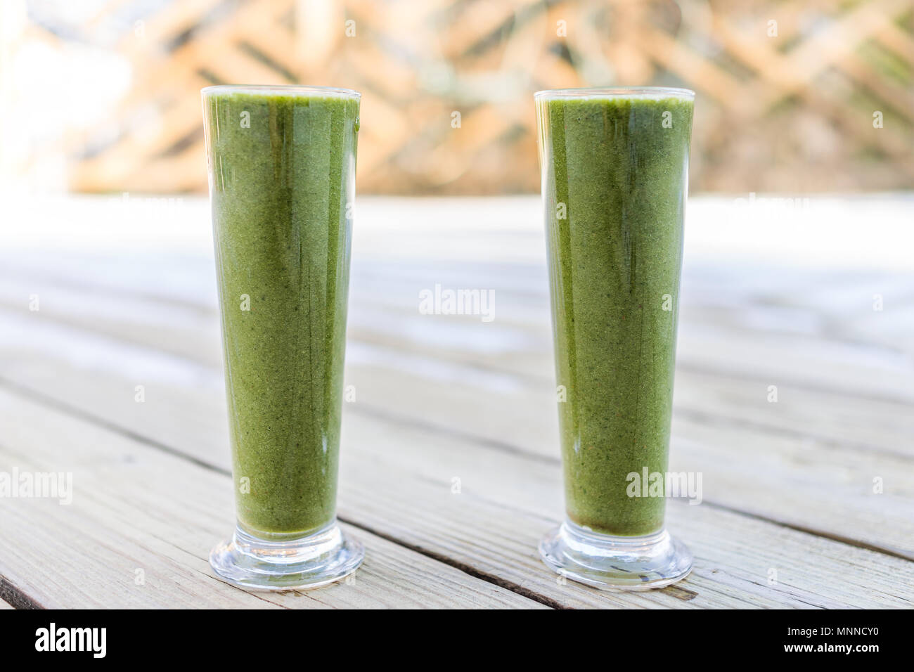 Closeup of two tall green vegetable fruit smoothies pair couple in ...