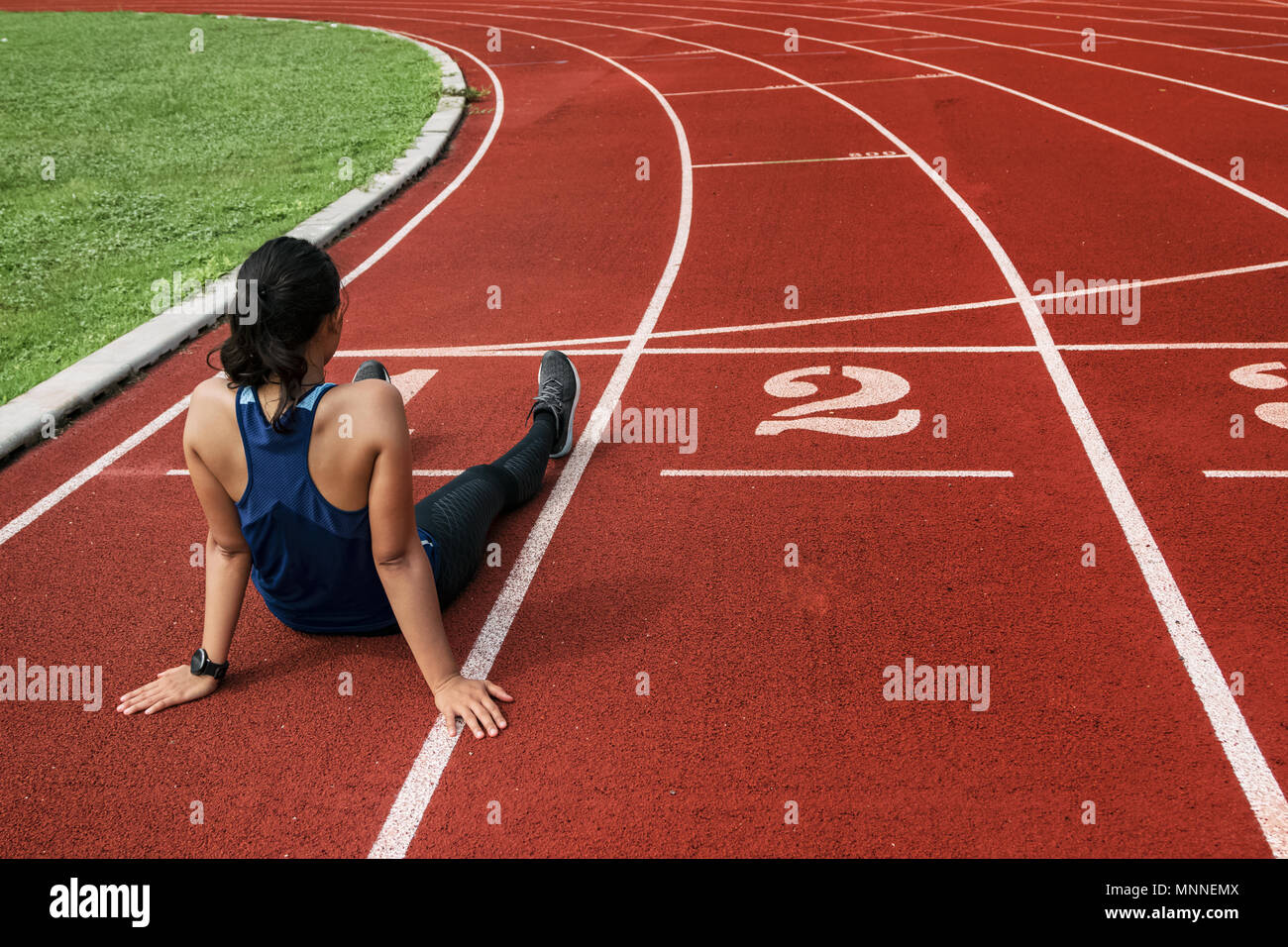 Female athlete tired after training and sitting on running track Stock ...