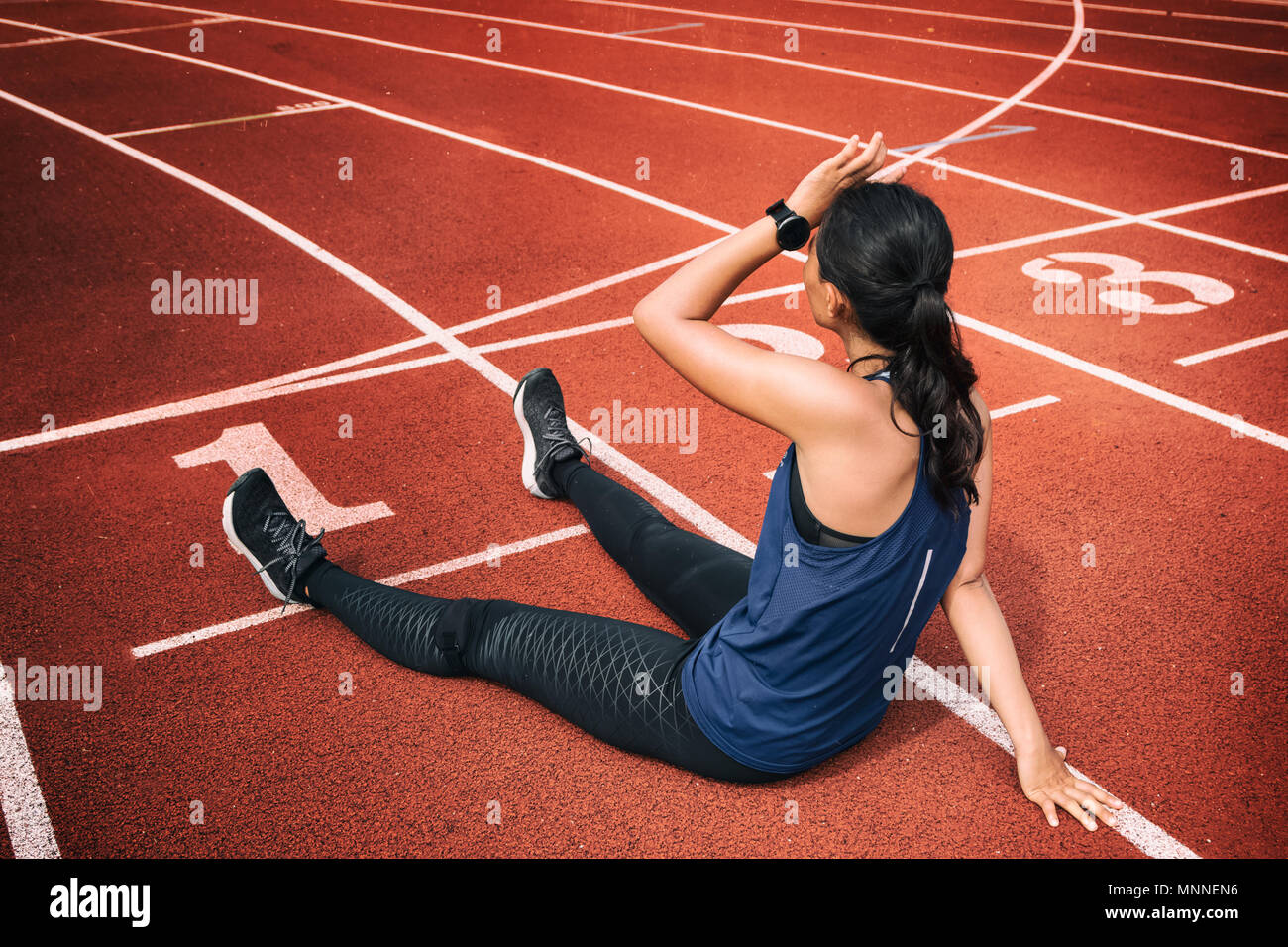 Female athlete tired after training and sitting on running track Stock ...
