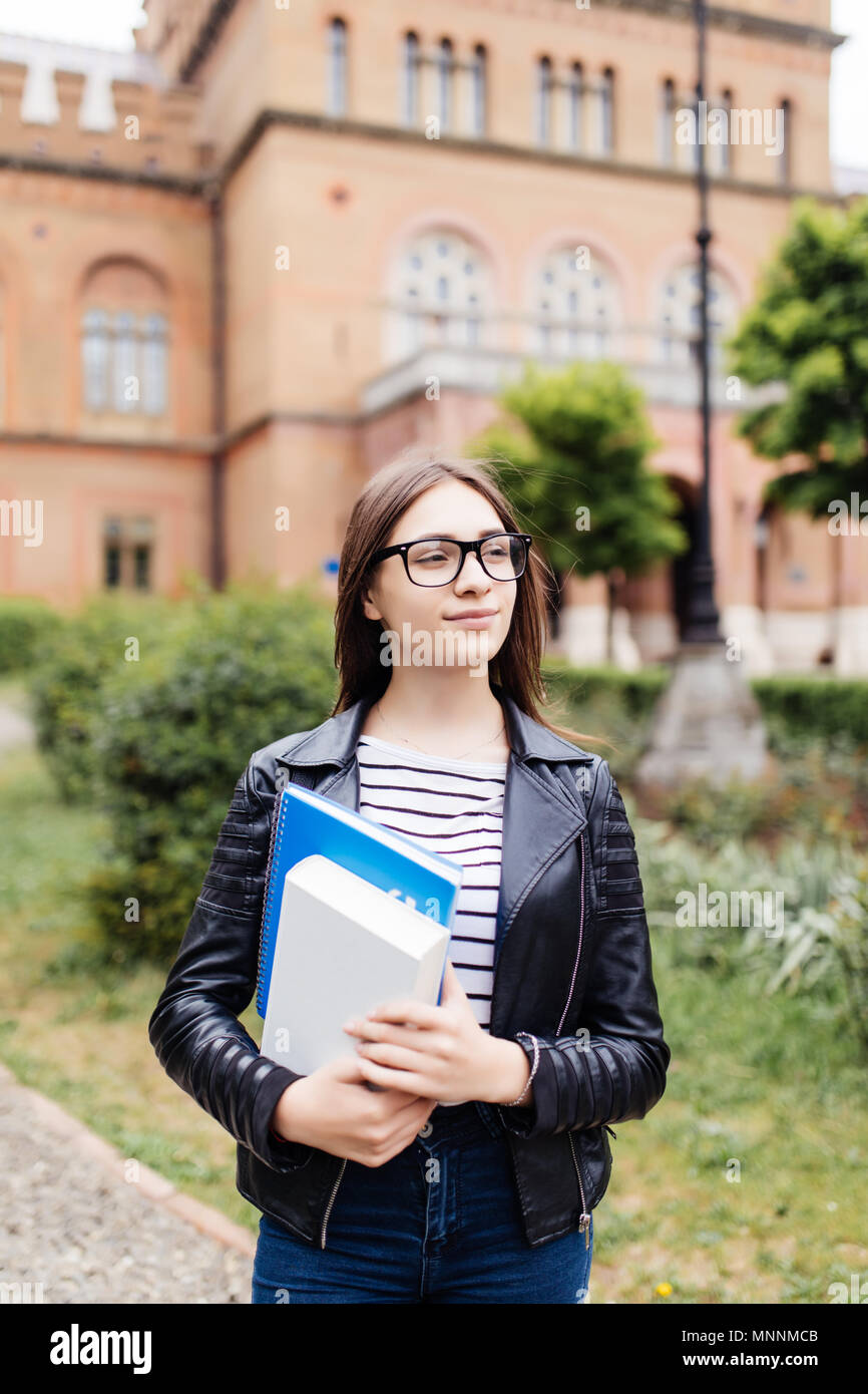 Female student holding notebooks outdoors and smiling Stock Photo - Alamy