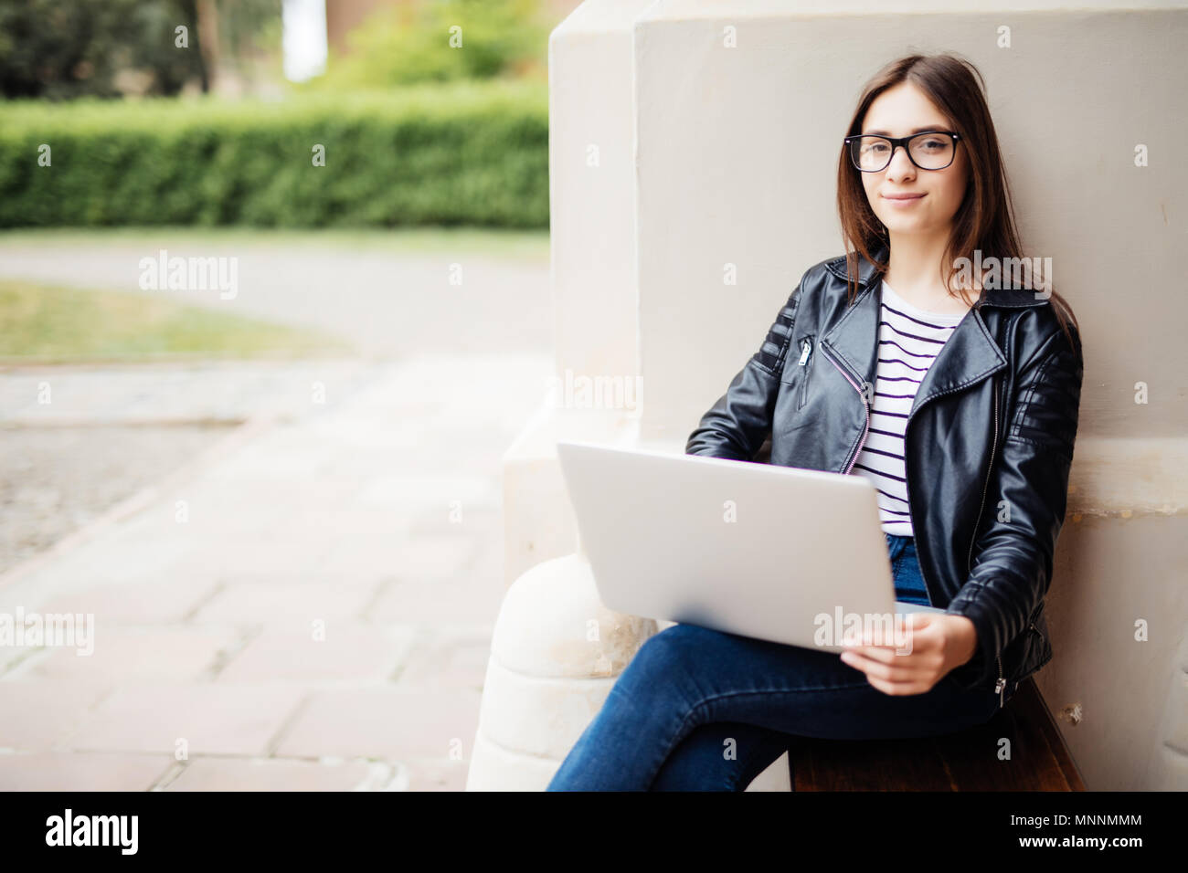 Smiling girl with laptop sitting crossed legs on the grass at ...