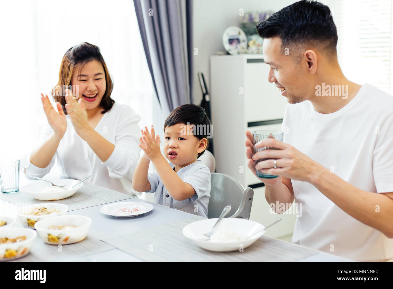 Asian parents clapping hands and giving compliment as their child does ...
