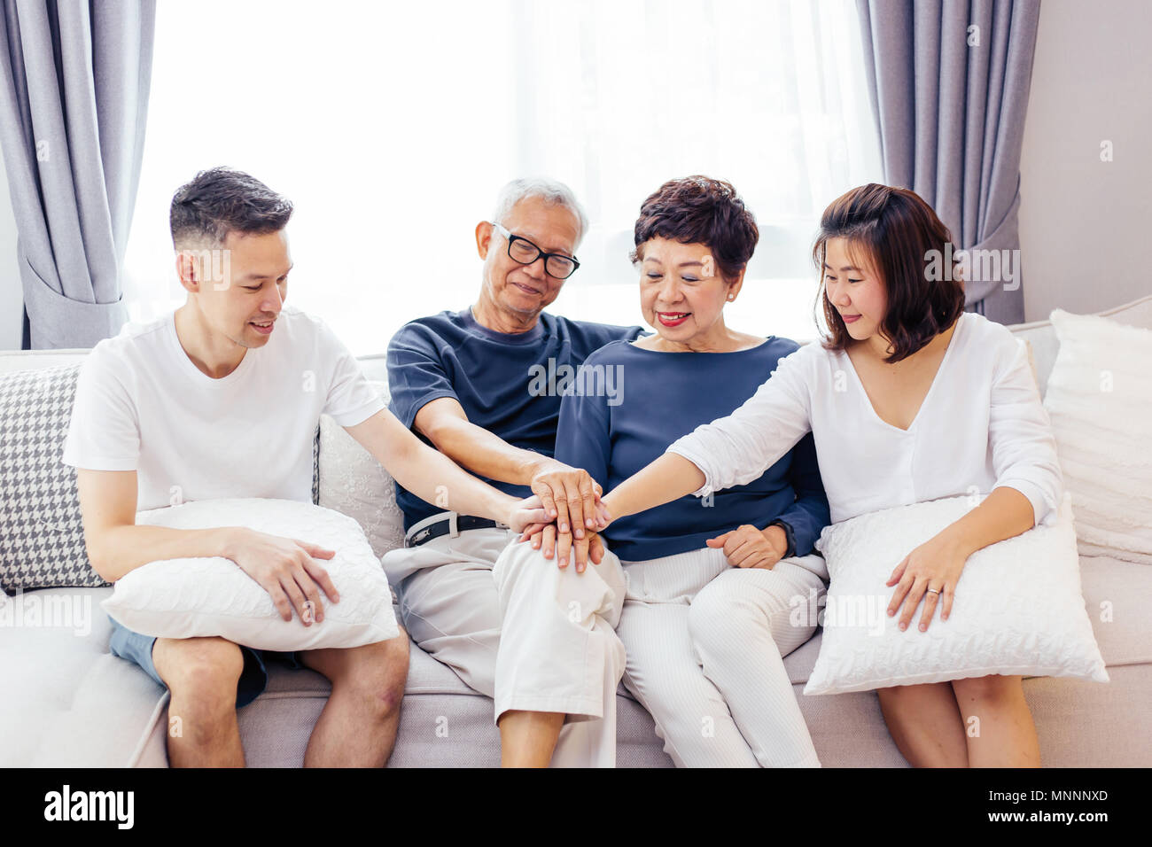 Asian family with adult children and senior parents putting hands ...