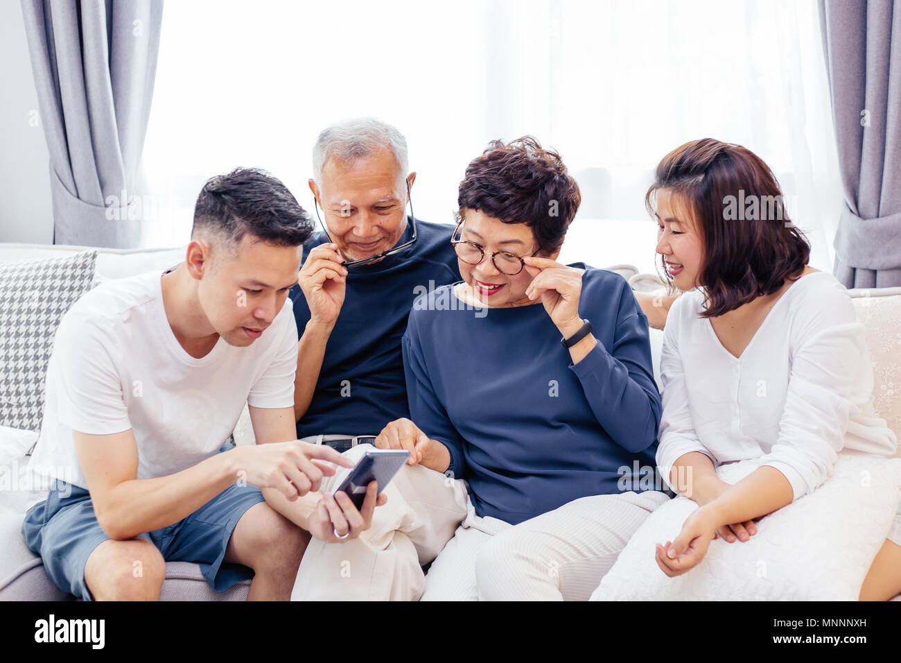 Asian family with adult children and senior parents using a mobile ...