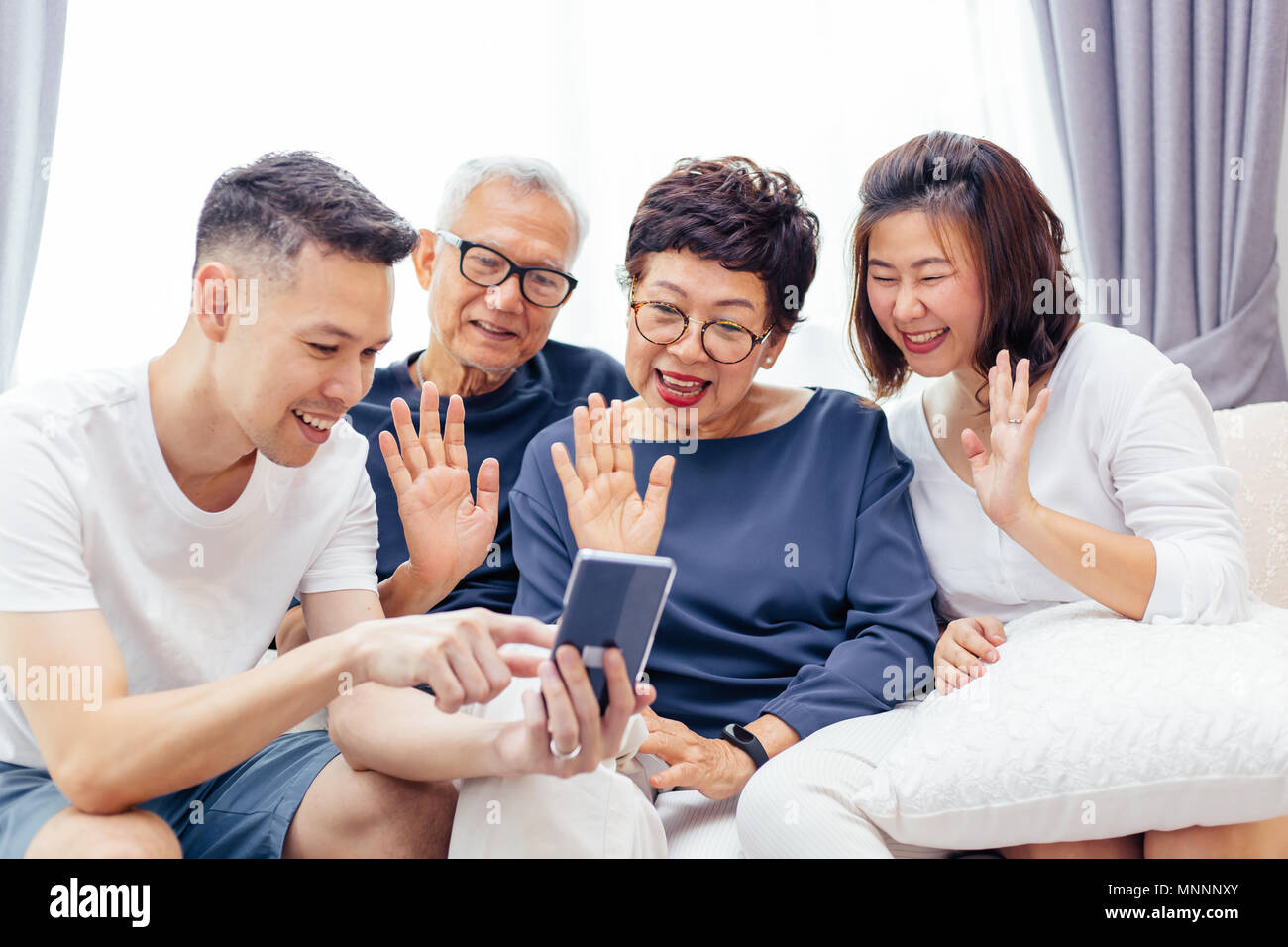 Extended family making a video call and waving at the caller. Asian ...