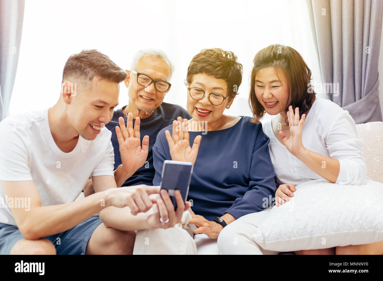 Extended family making a video call and waving at the caller. Asian ...