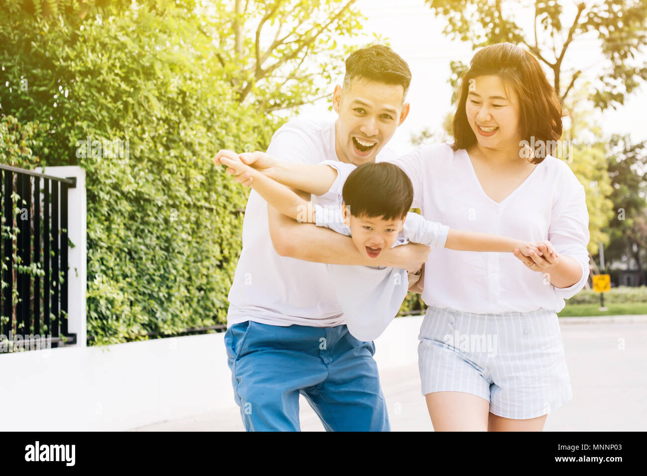 Asian family having fun and carrying a child in public park Stock Photo ...