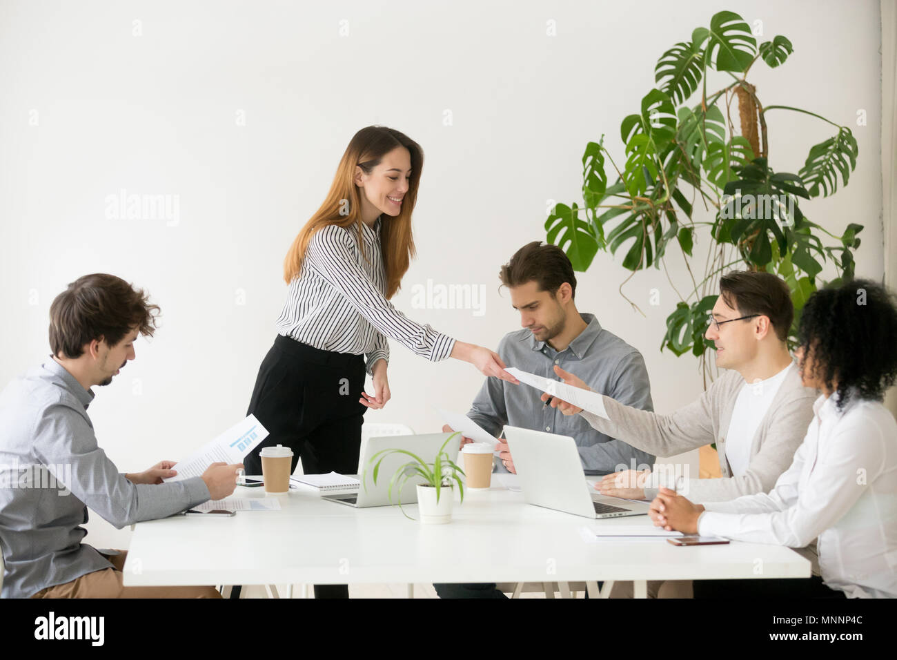 Smiling businesswoman giving partners project documents for revi Stock ...