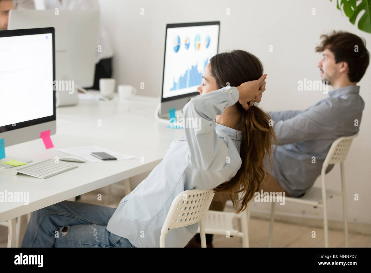 Female employee relaxing from computer work holding hands behind Stock ...