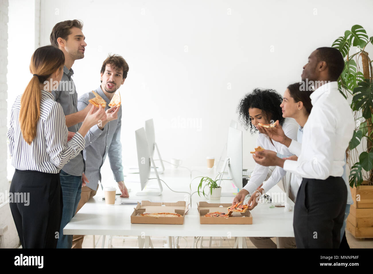 Friendly diverse business team talking eating pizza together in Stock ...