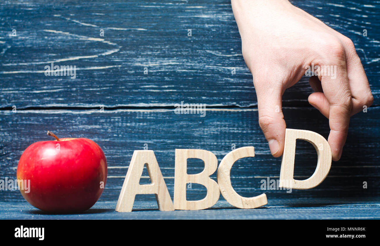 Red apple and letters ABCD. The hand puts the letter D in the alphabet ...