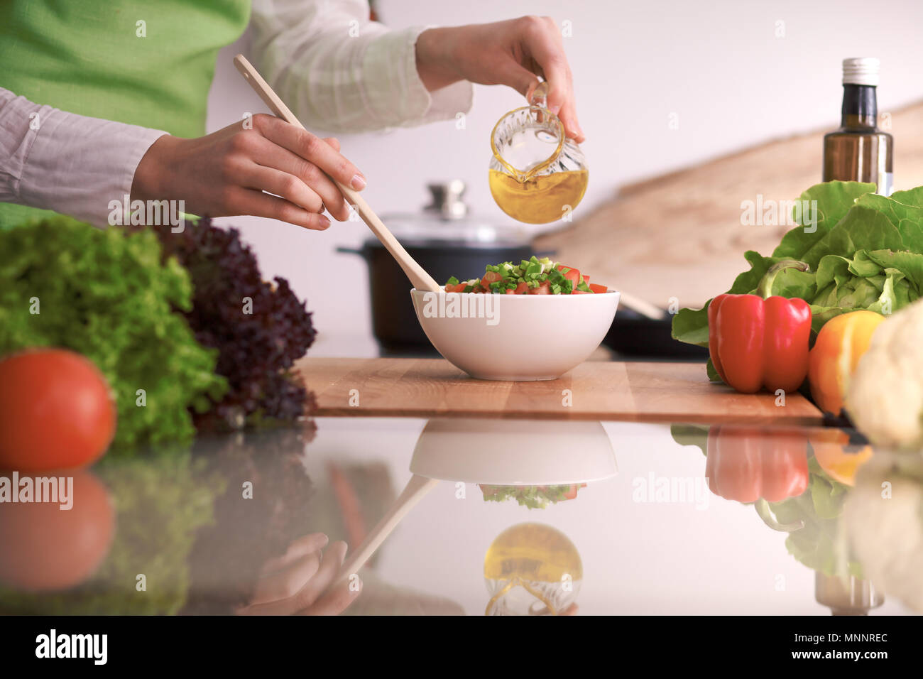 Close Up of human hands cooking vegetable salad in kitchen on the glass ...