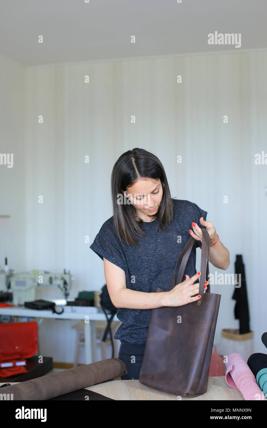 Creative woman making brown leather handmade bag at atelier Stock Photo ...