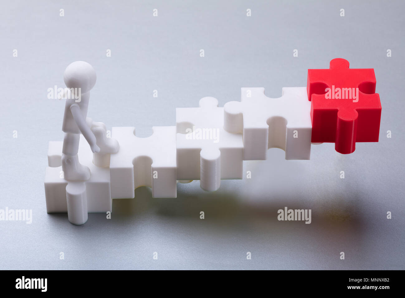 Side View Of A Human Figure Climbing Jigsaw Puzzle Over Grey Background ...