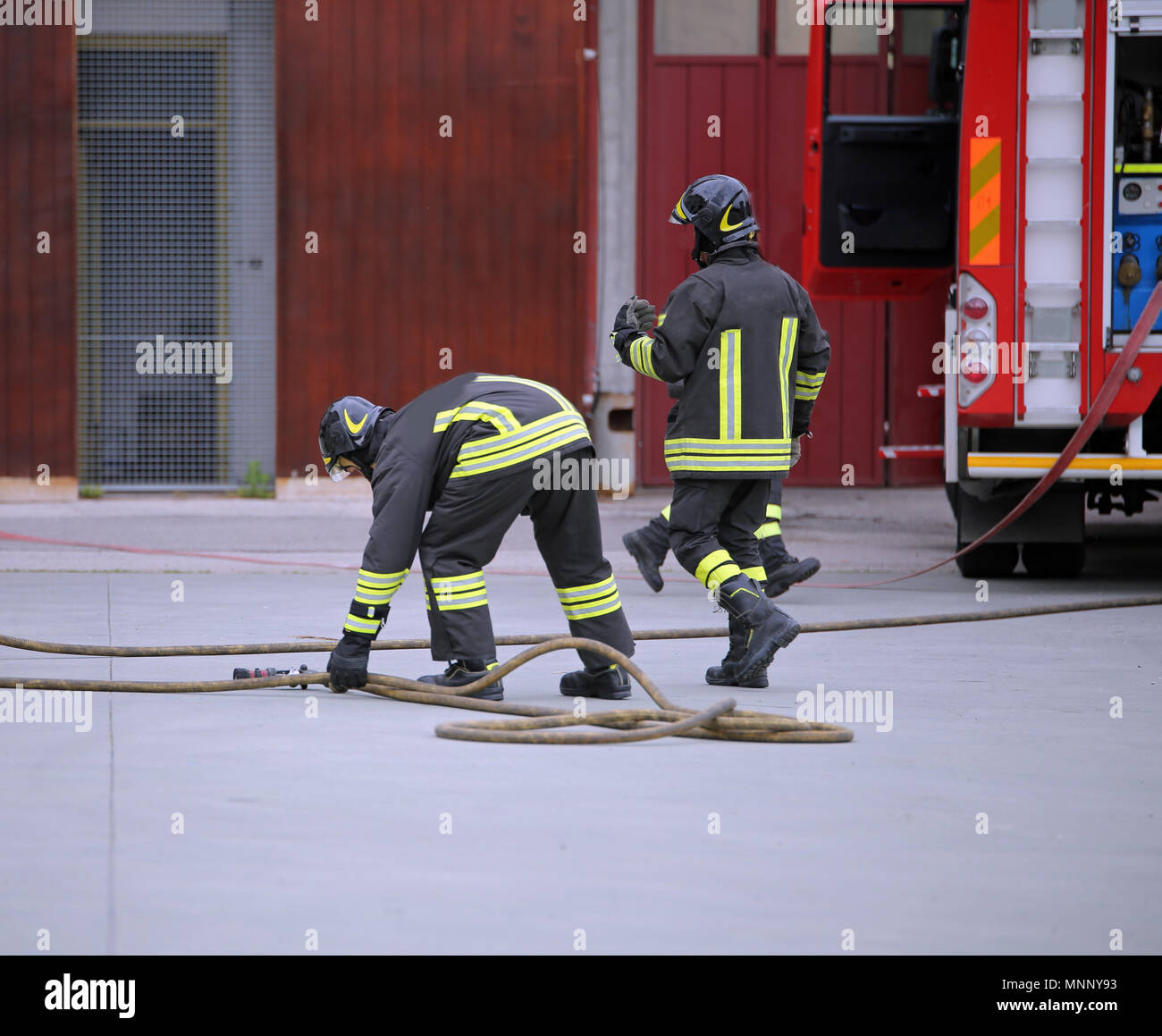 two firefighters shooting in action unroll the water pipes Stock Photo ...