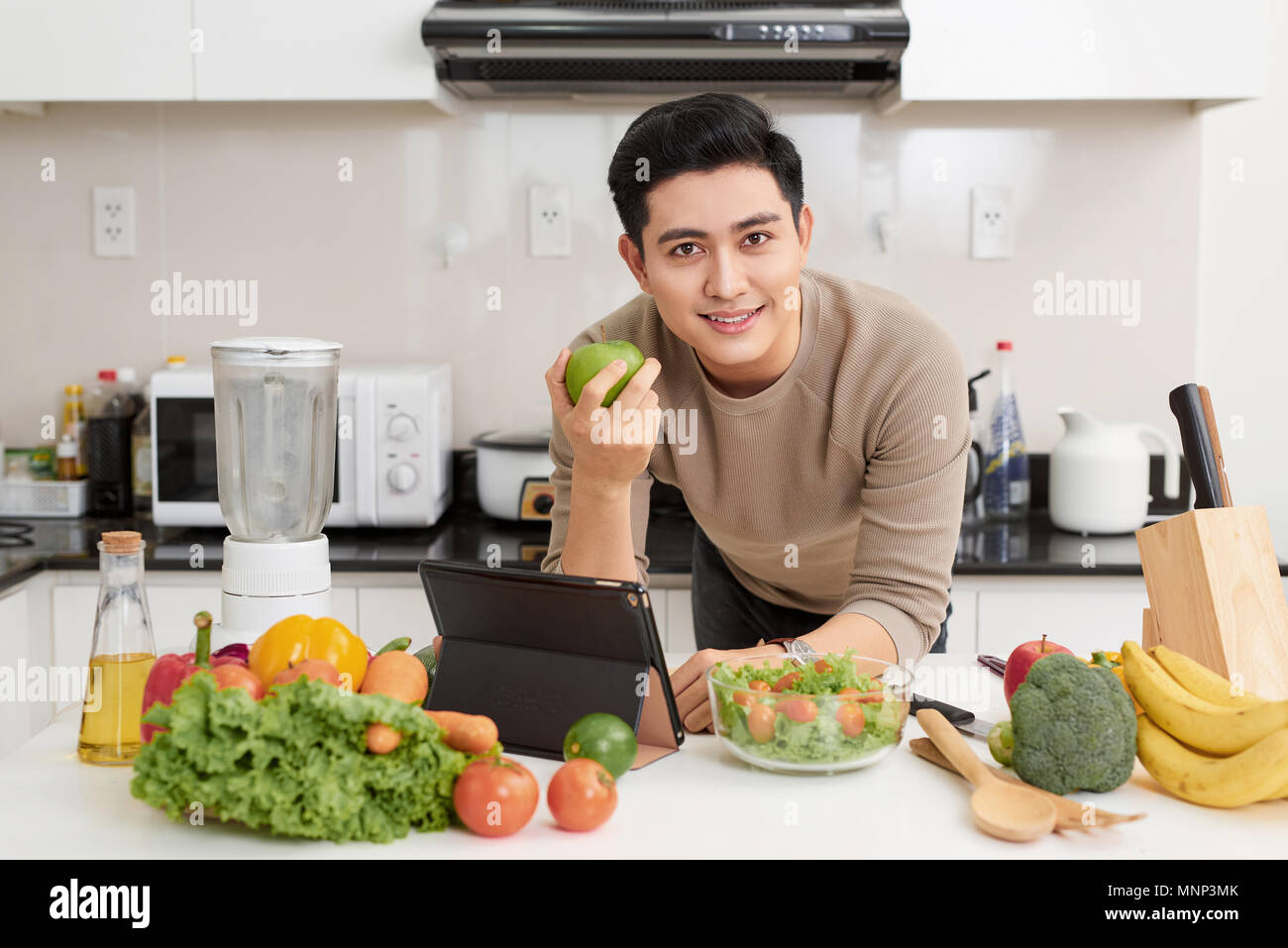 Asian handsome man looking recipe on laptop in kitchen at home Stock ...
