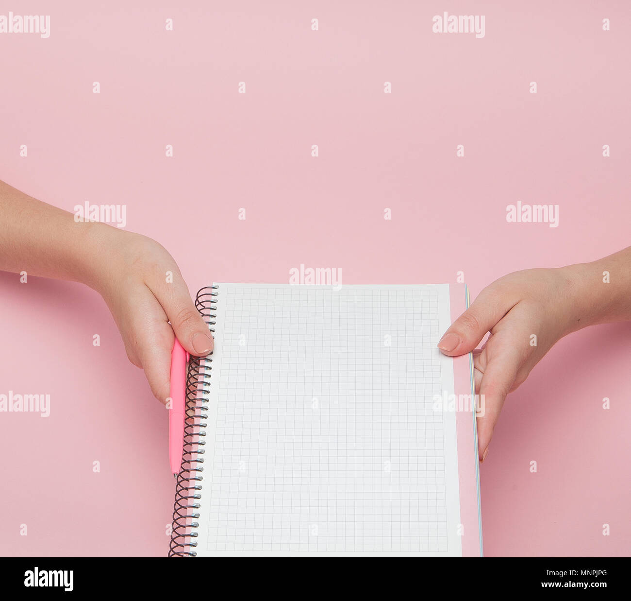 Notebook and pen in hand on pink background with copy space.Business ...