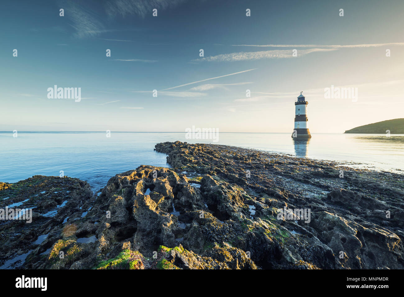 Penmon Lighthouse and moss covered rocks in bright sunnlight. Anglesey ...