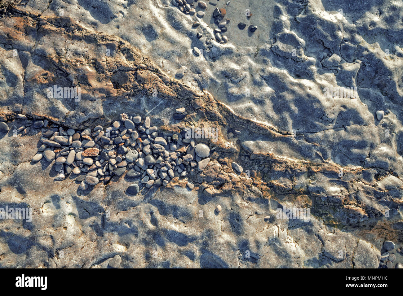 Surface of heavilly eroded marine cliff rock in brown-grey colours ...