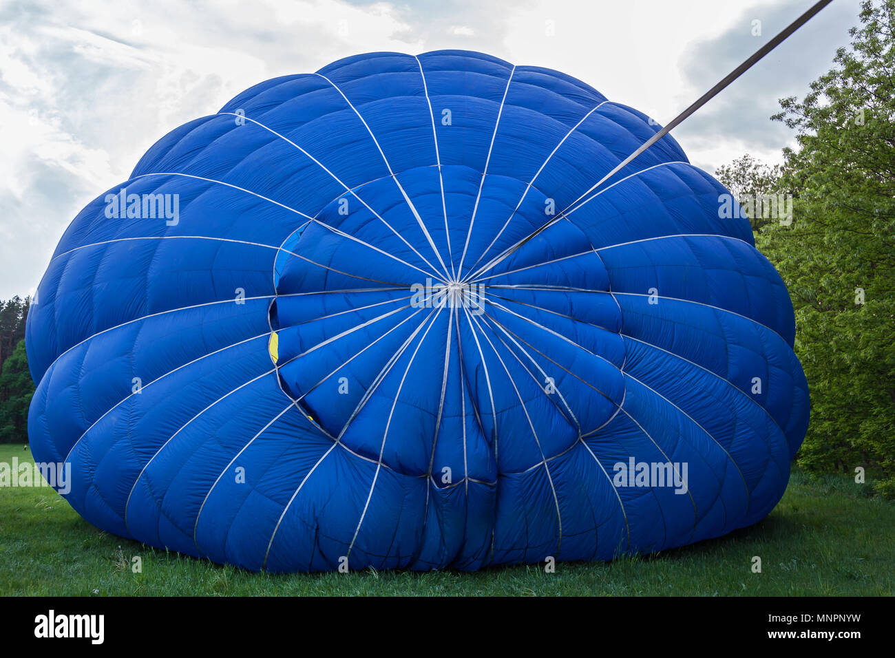 A balloon with a basket lies on the ground, equipment for filling the ...