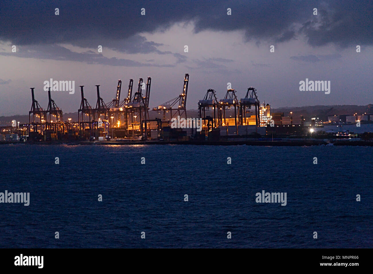 a container pier with cargo boxes and cranes in the early morning light ...