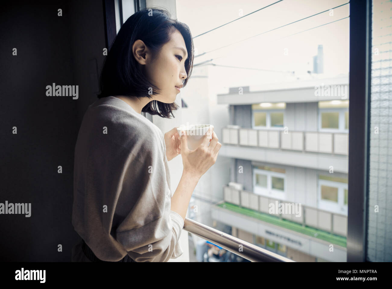 Japanese woman sitting in a traditional Tokyo apartment and drinking a ...