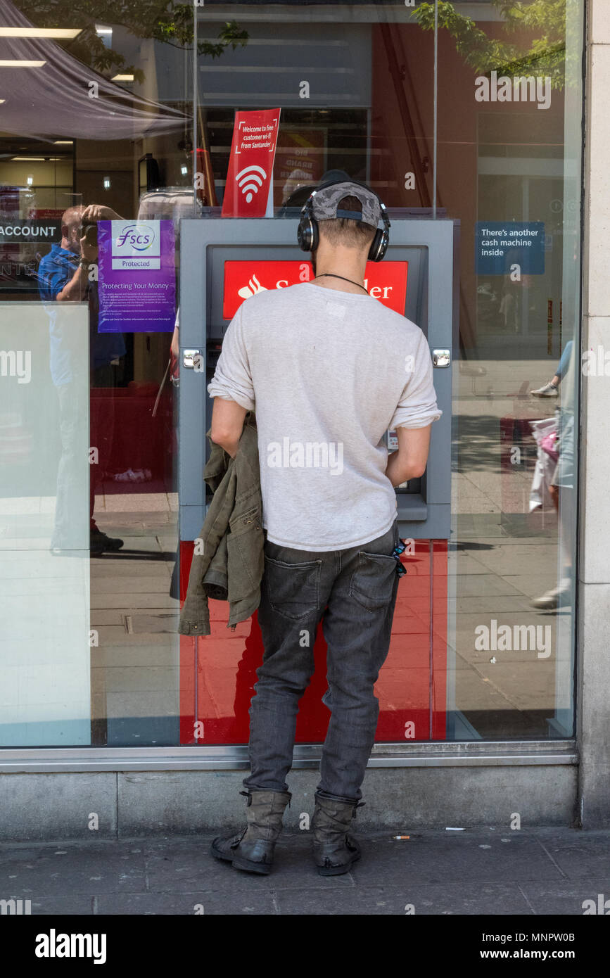 a young man wearing a baseball cap and some headphones using a cahpoint ...