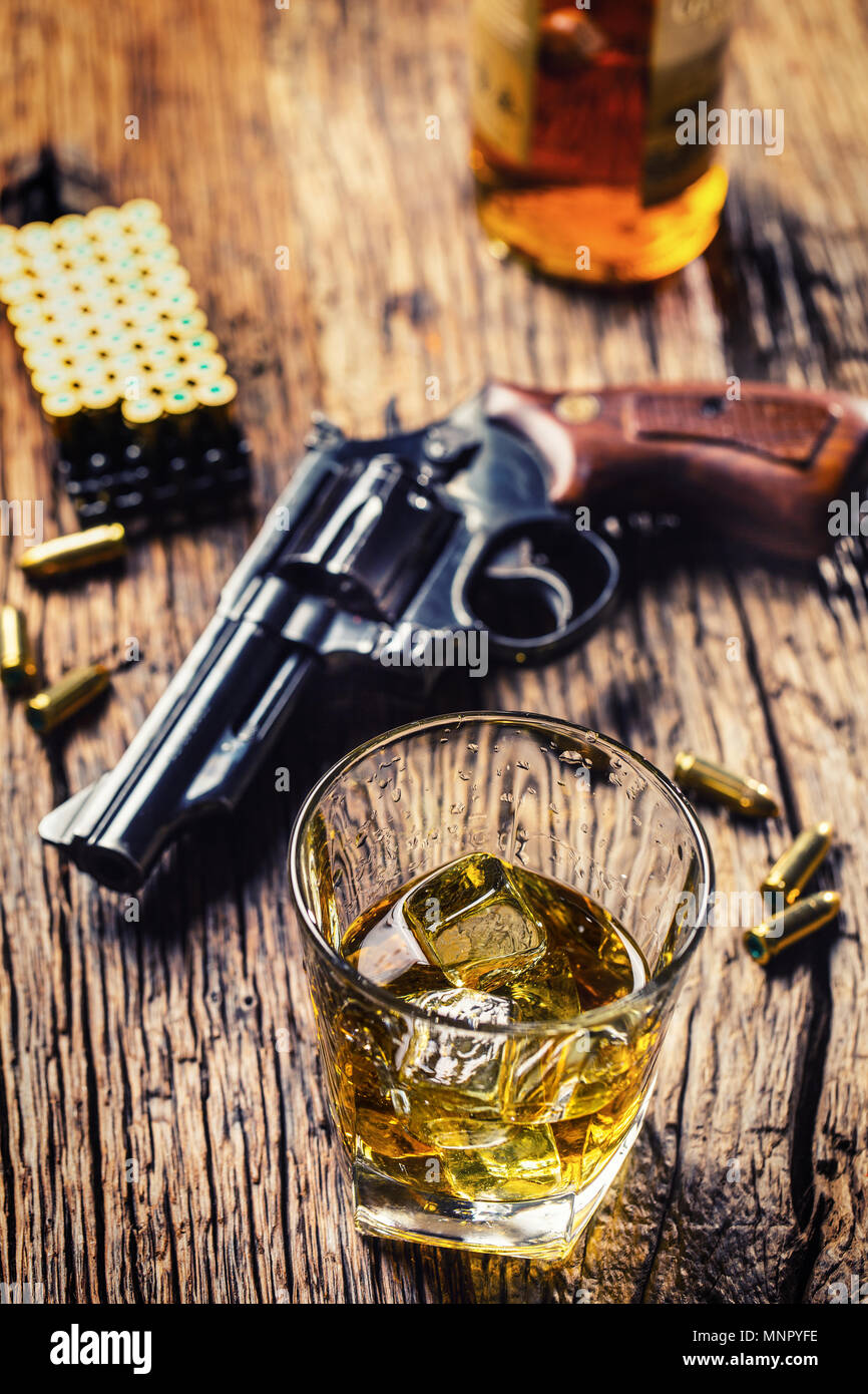 Glass of whiskey cognac or bourbon with revolver and bullets on wooden ...