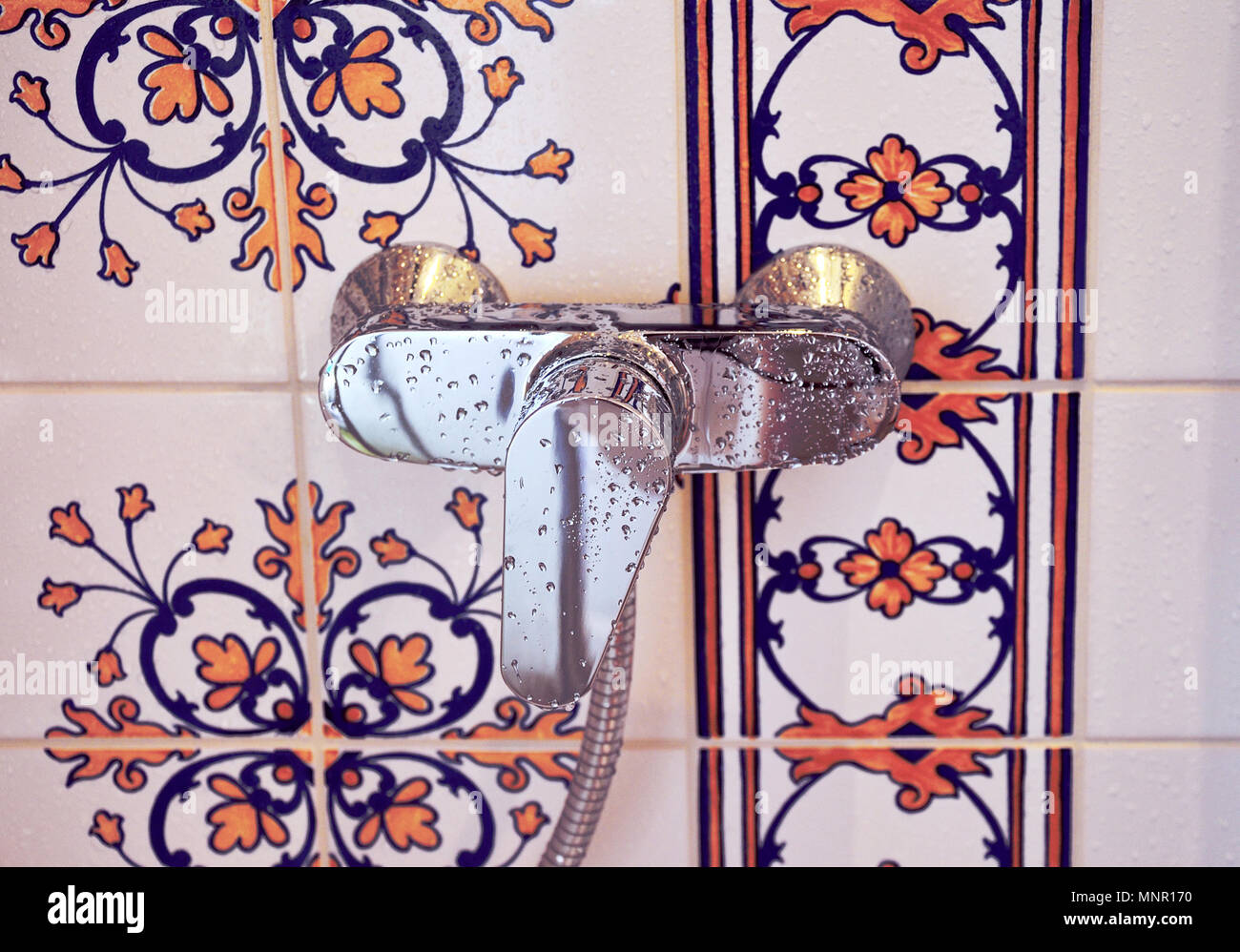 Closeup of shiny shower faucet with waterdrops and beautiful tiles in ...