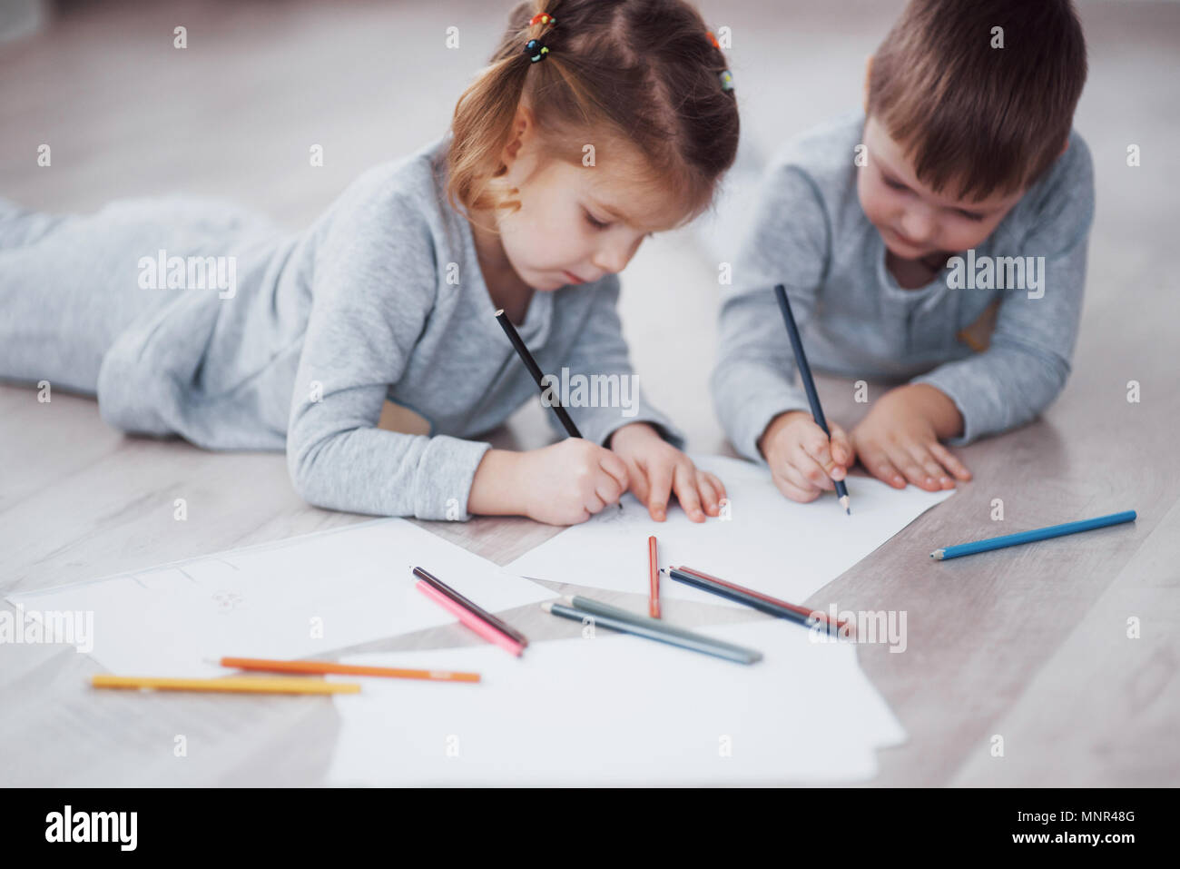 Children lie on the floor in pajamas and draw with pencils. Cute child ...
