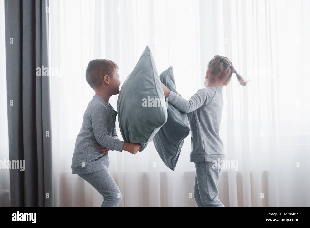 Little boy and girl staged a pillow fight on the bed in the bedroom ...