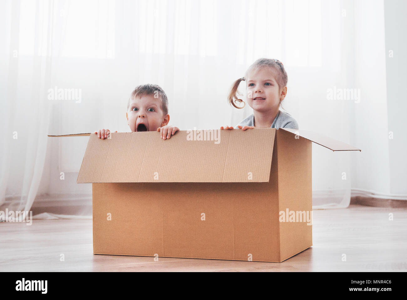 Two a little kids boy and girl playing in cardboard boxes. Concept ...