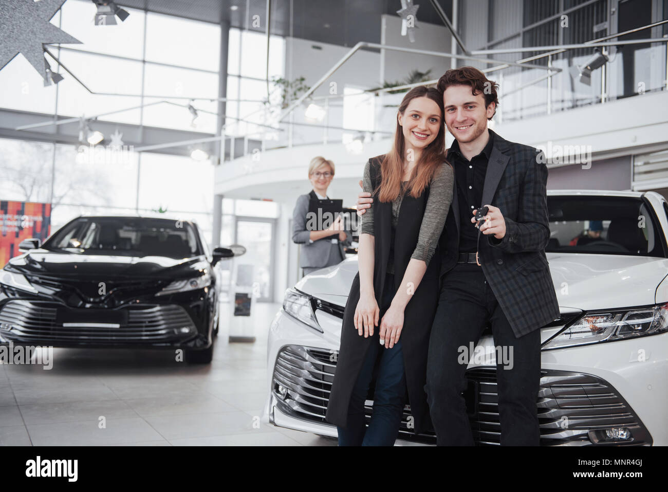 Our first car. Beautiful happy woman smiling showing the keys to a new ...