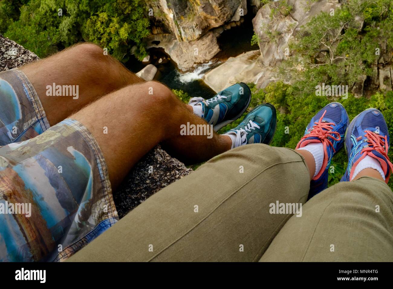 Legs hanging over a cliff with a waterfall down below, Jourama Falls ...