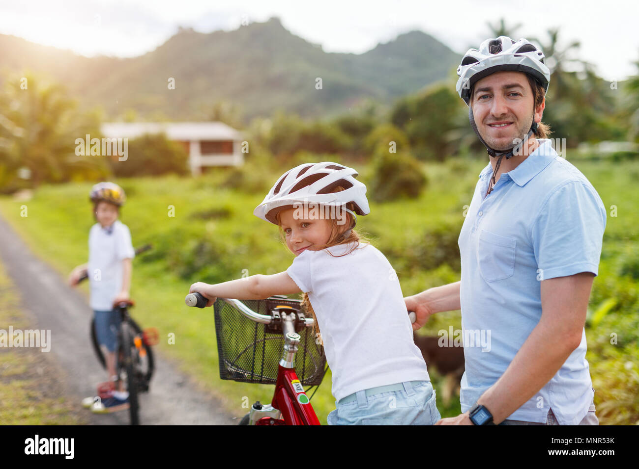 Family of father and kids biking at tropical settings Stock Photo - Alamy