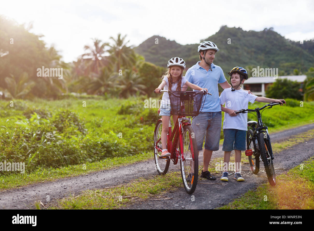 Family of father and kids biking at tropical settings Stock Photo - Alamy