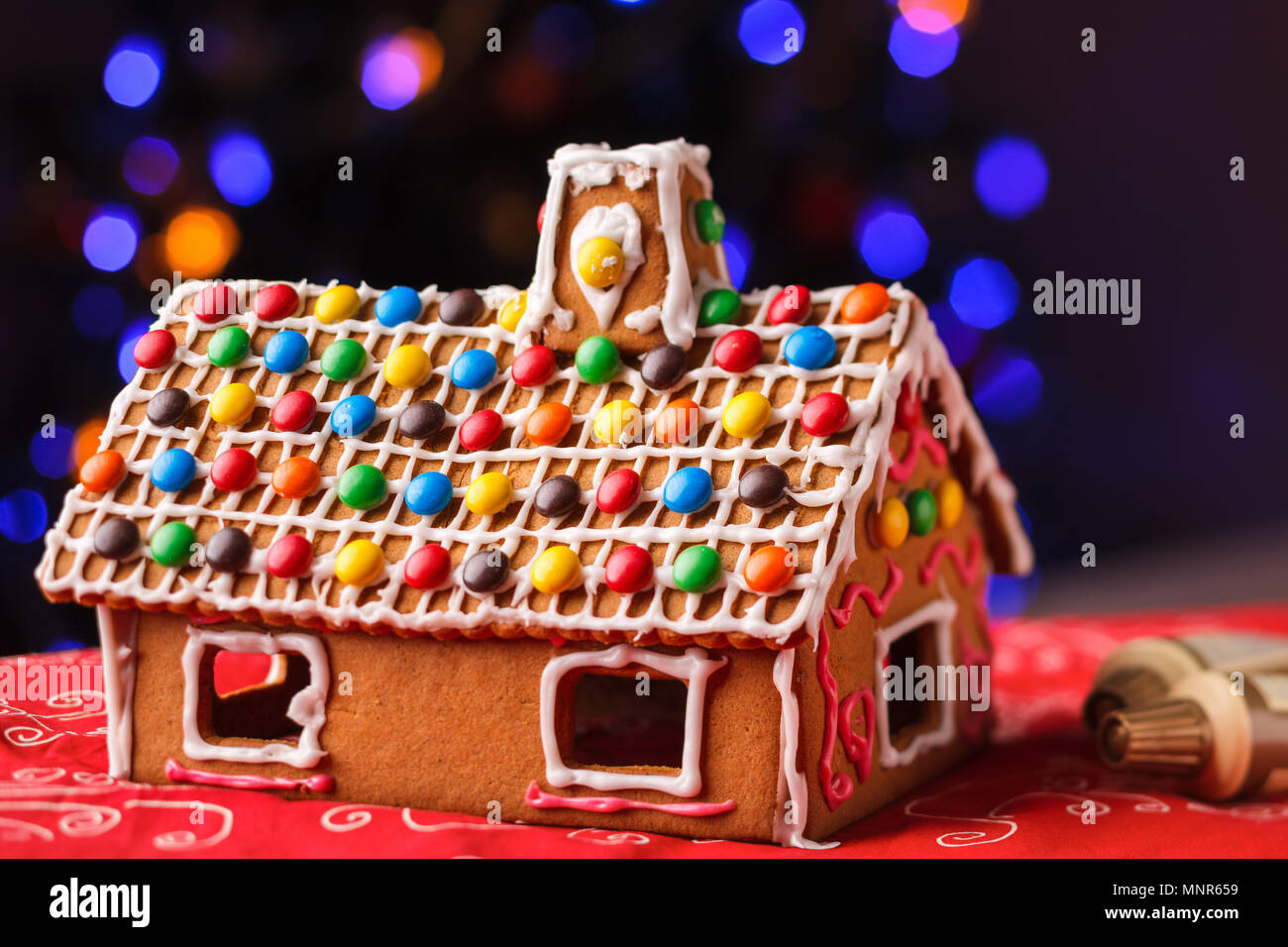 Gingerbread house decorated with colorful candies over Christmas tree ...