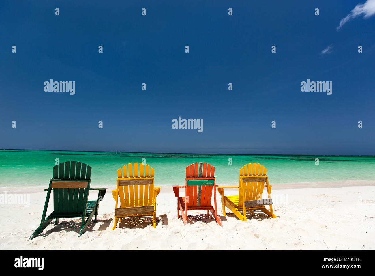 Row of colorful wooden chairs at tropical white sand beach in Caribbean ...
