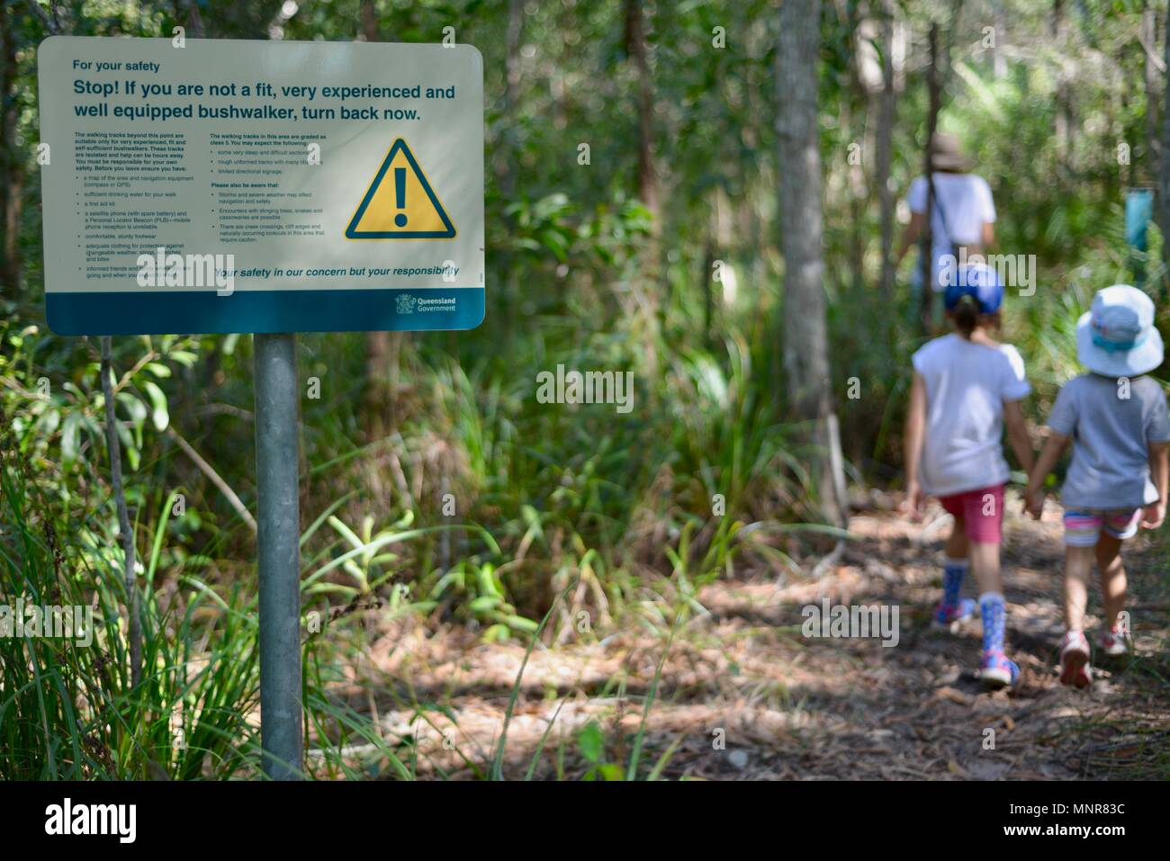 Young children walking past a Warning sign at start of Mount Halifax ...