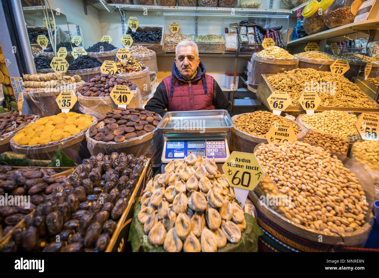 Adult male shop merchant stands behind counter that has baskets full of ...