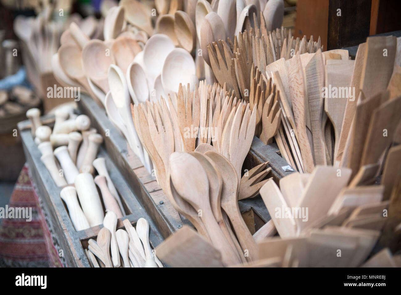 Wooden kitchen utensils laid out in bins at outdoor marketplace ...