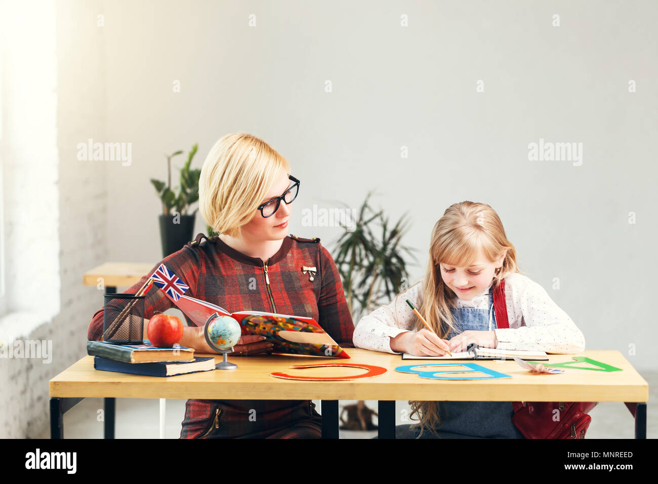 Elegant English teacher wears eyeglasses studying with kid school girl ...