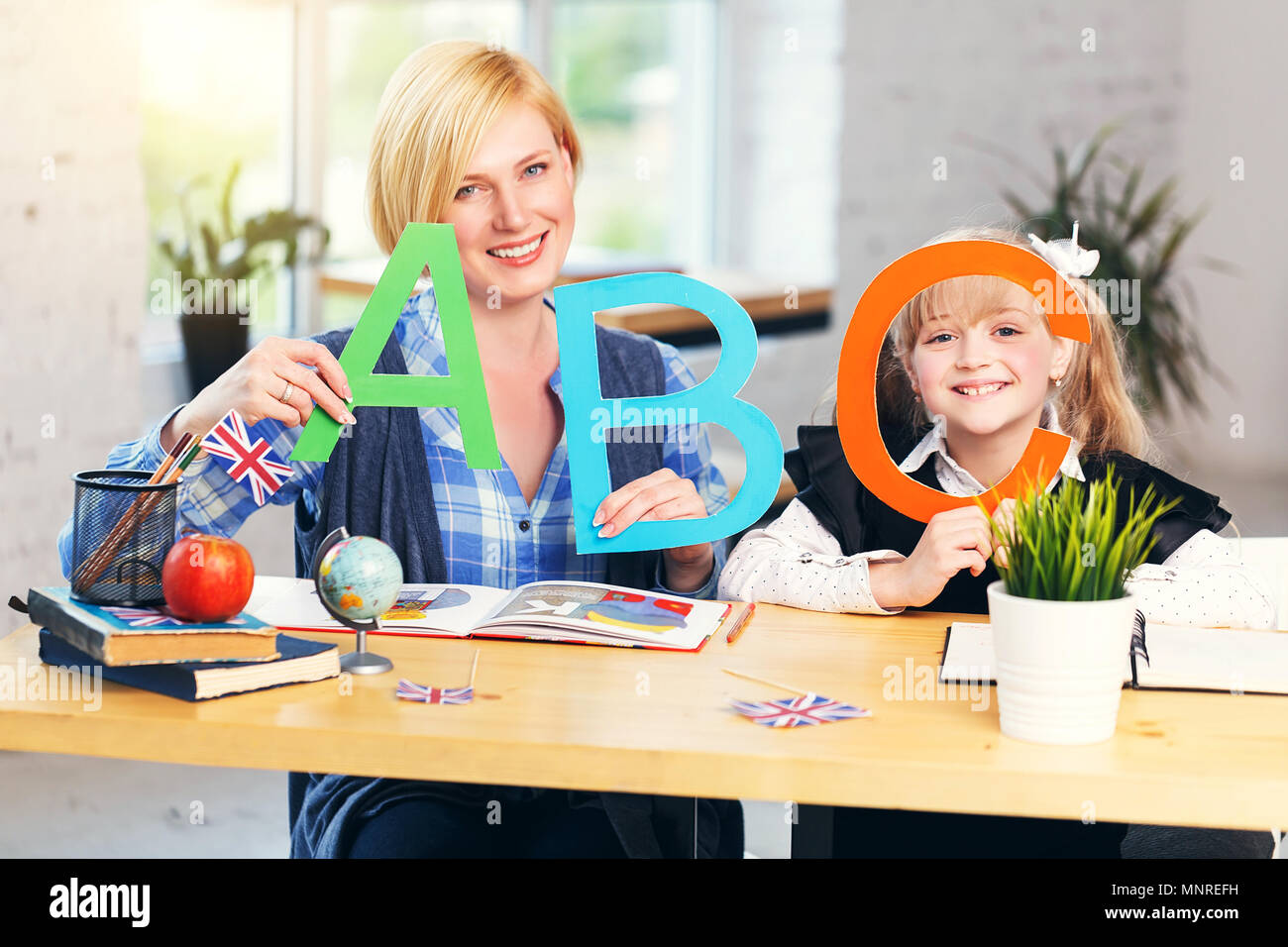 Smiling blonde English teacher plays letters and words with kid school ...