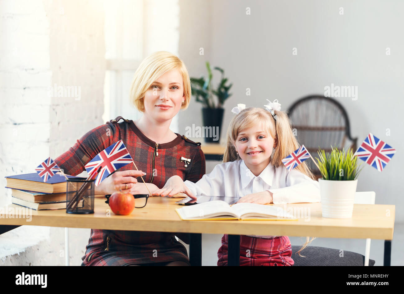 Female educator of English and smart girl smiling, working table with ...