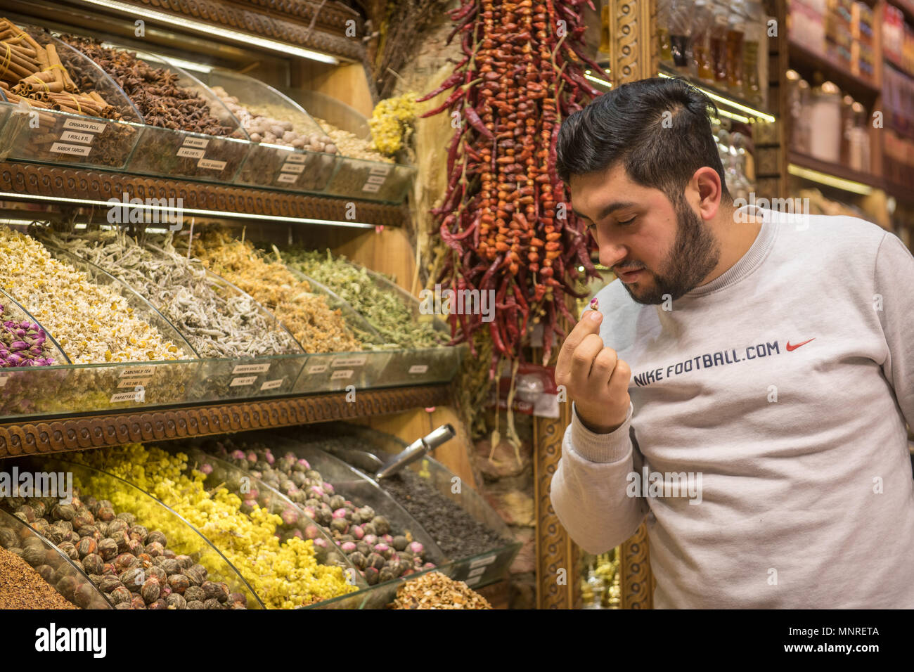 Adult male merchant carefully inspects flower tea in spice shop in ...