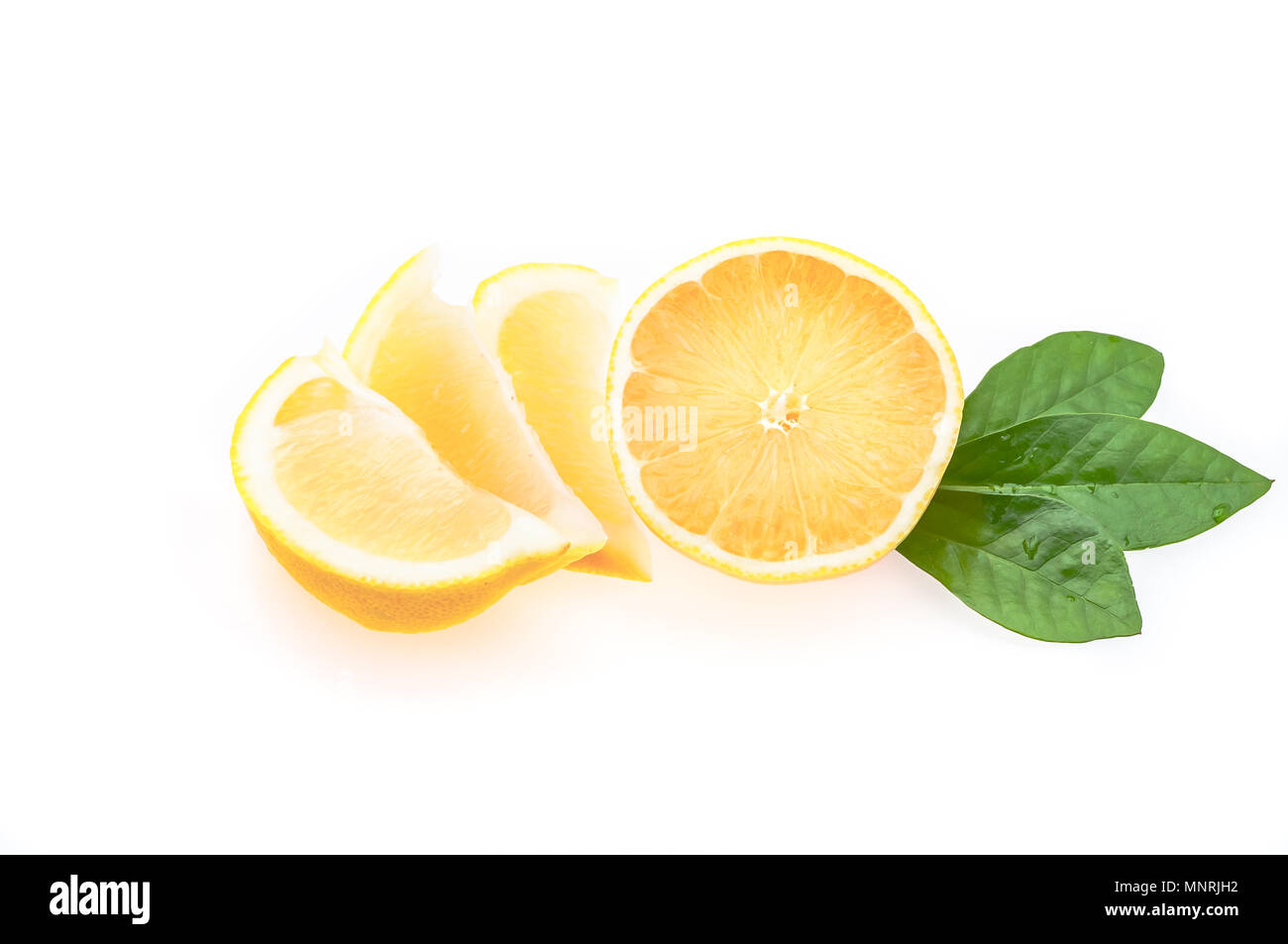 Half a fresh, glowing lemon with green leaves and several cut slices on ...