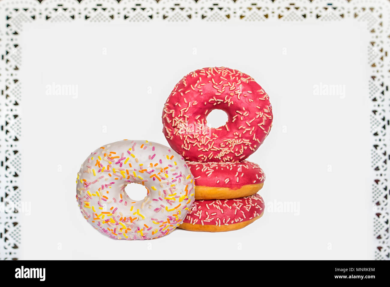 four donuts with a pink icing on a white background Stock Photo - Alamy