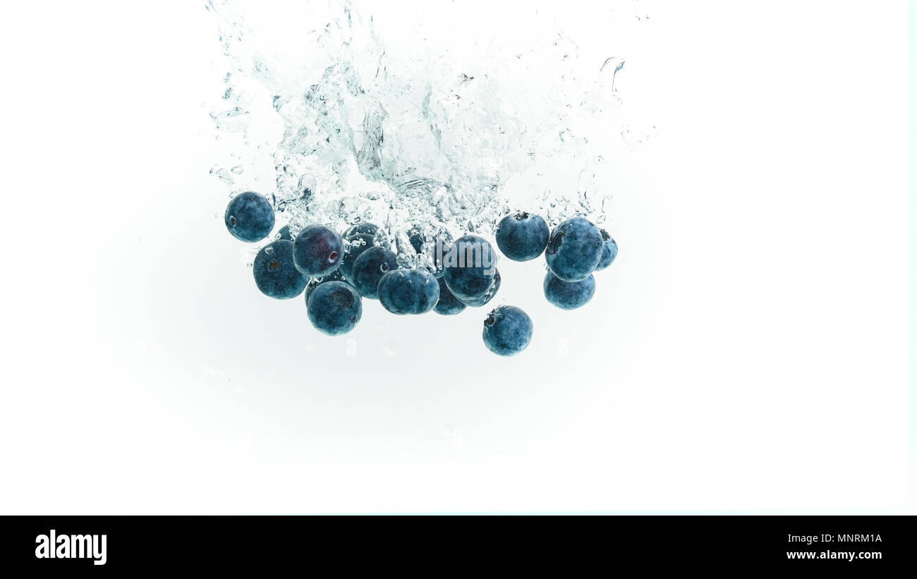 Blueberries sinking into water with air bubbles white background Stock ...